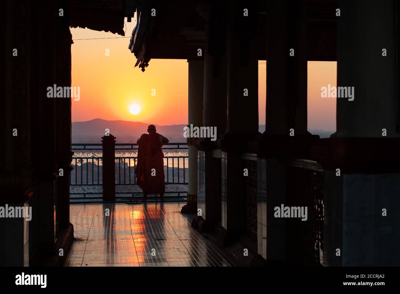 Buddhist monk pictured from behind. Looking at the beautiful sunset ...