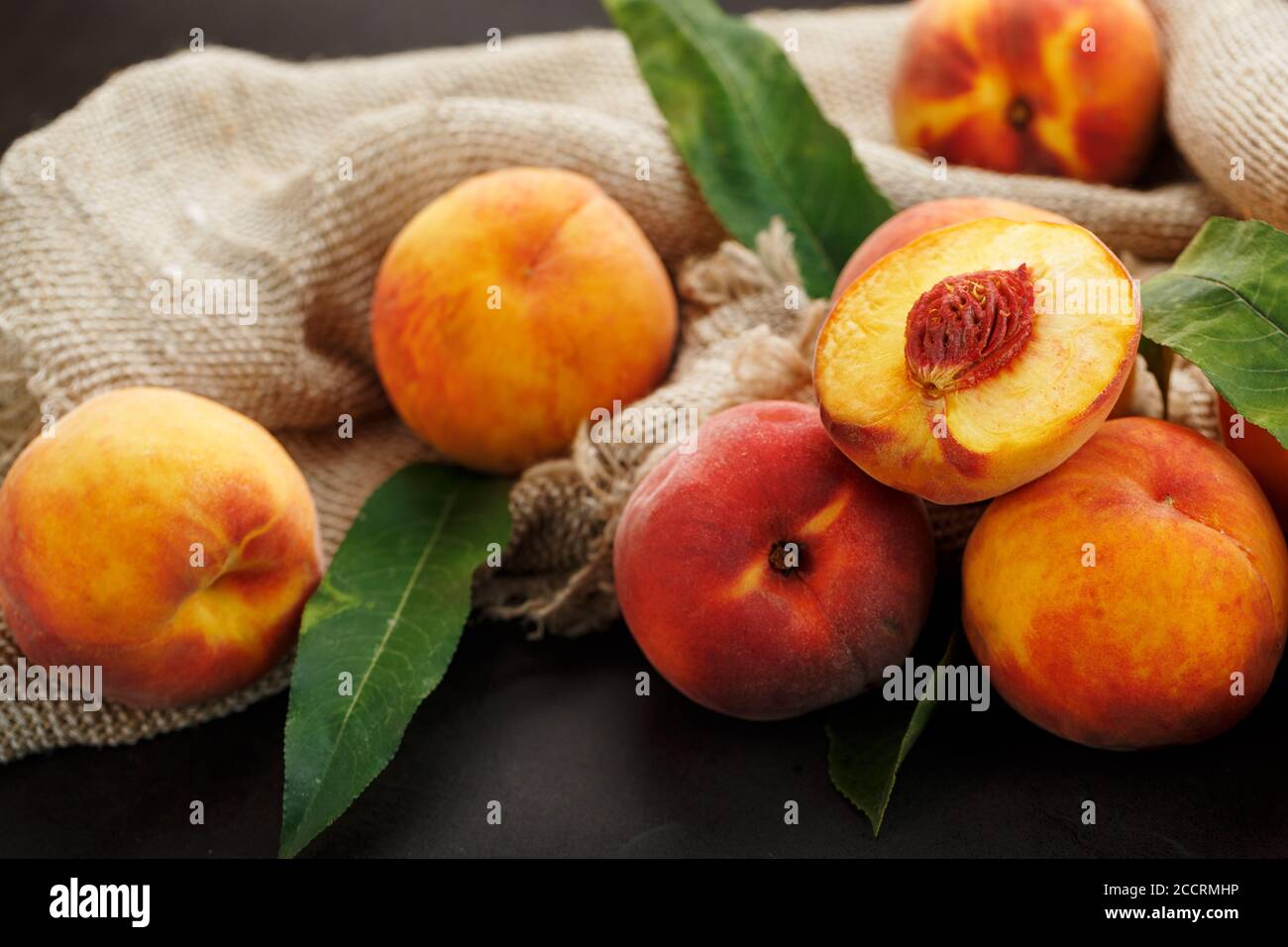 Sweet Peaches on a sharp stone table with a cloth of burlap and a slice ...