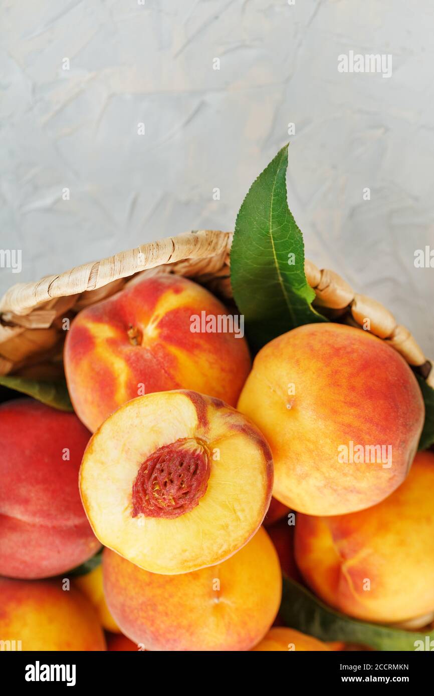 Ripe peaches in a wicker basket on a stone gray table with a juicy ...