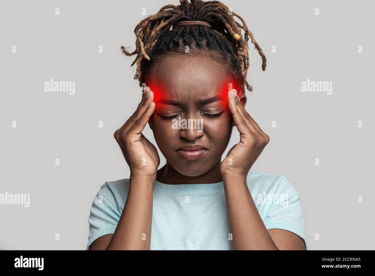Upset african girl touching her lightened with red temples Stock Photo ...