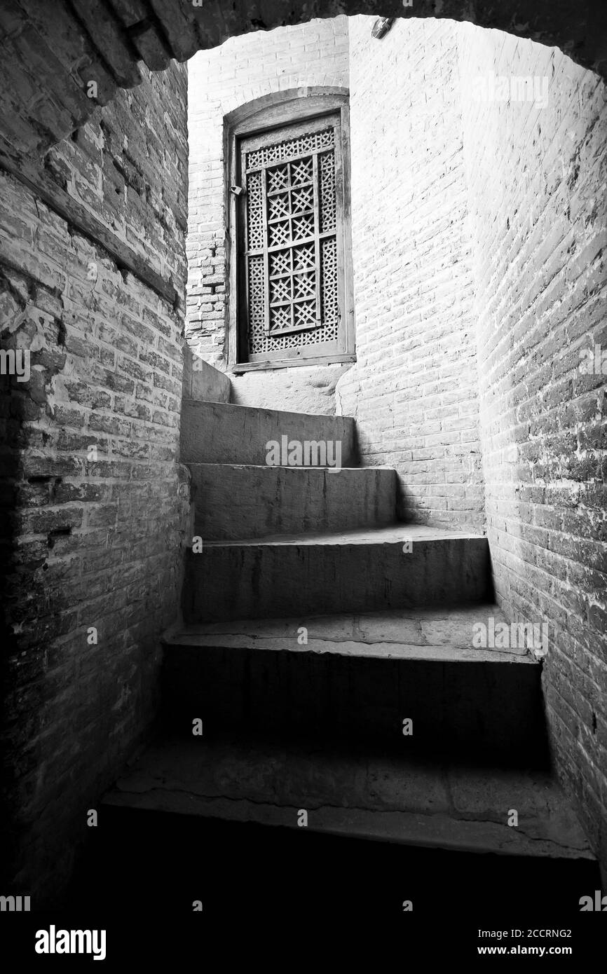 An old spiral staircase and brick wall with an Islamic window with an ...