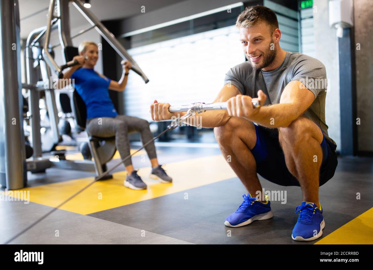 Portrait of fit handsome man workout on a fitness machine at gym Stock ...