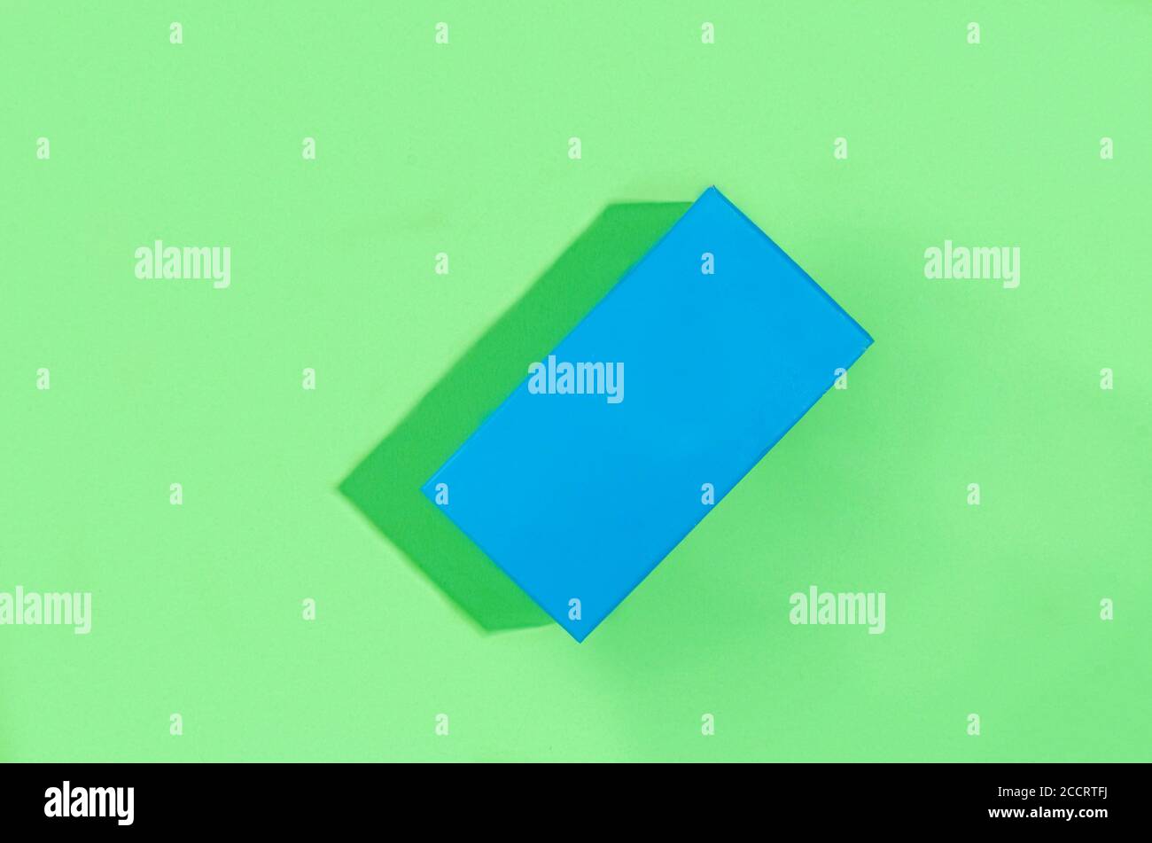 Blue geometric figure, a rectangular with shadows on a light green ...