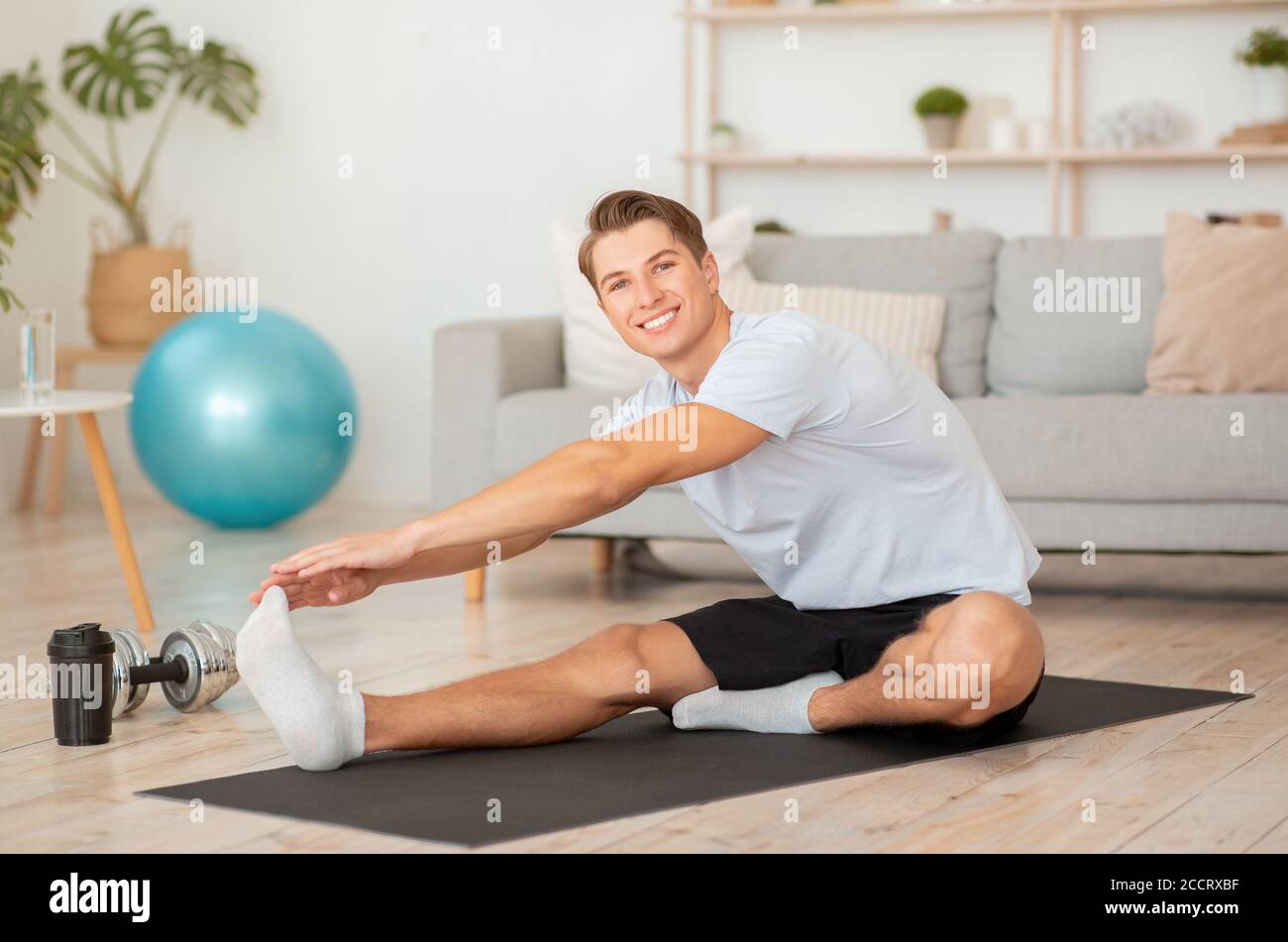 Stretching at home after exercise. Happy guy coach makes video for ...