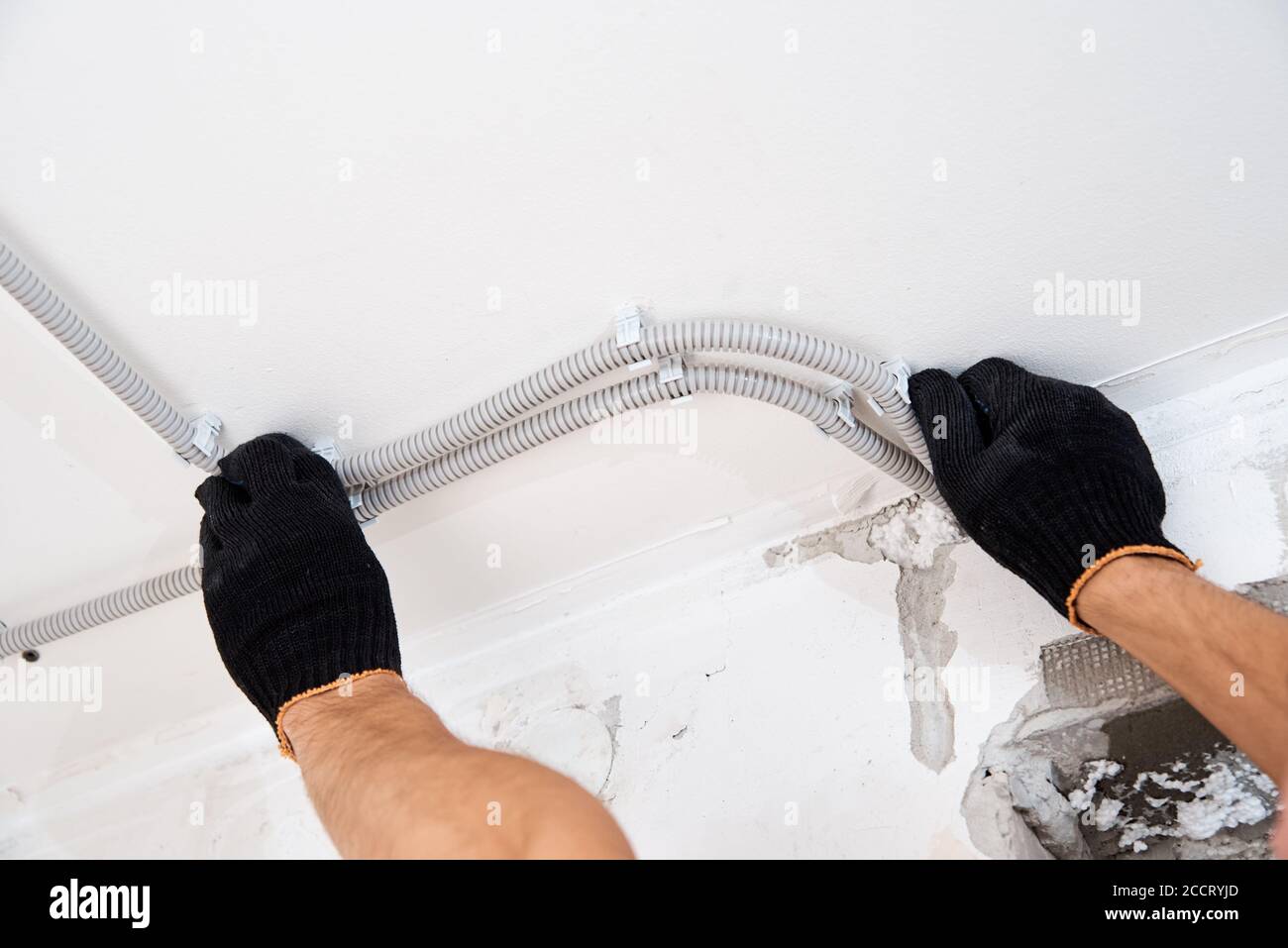 Electrician fixing electric cable to the wall, close up Stock Photo - Alamy