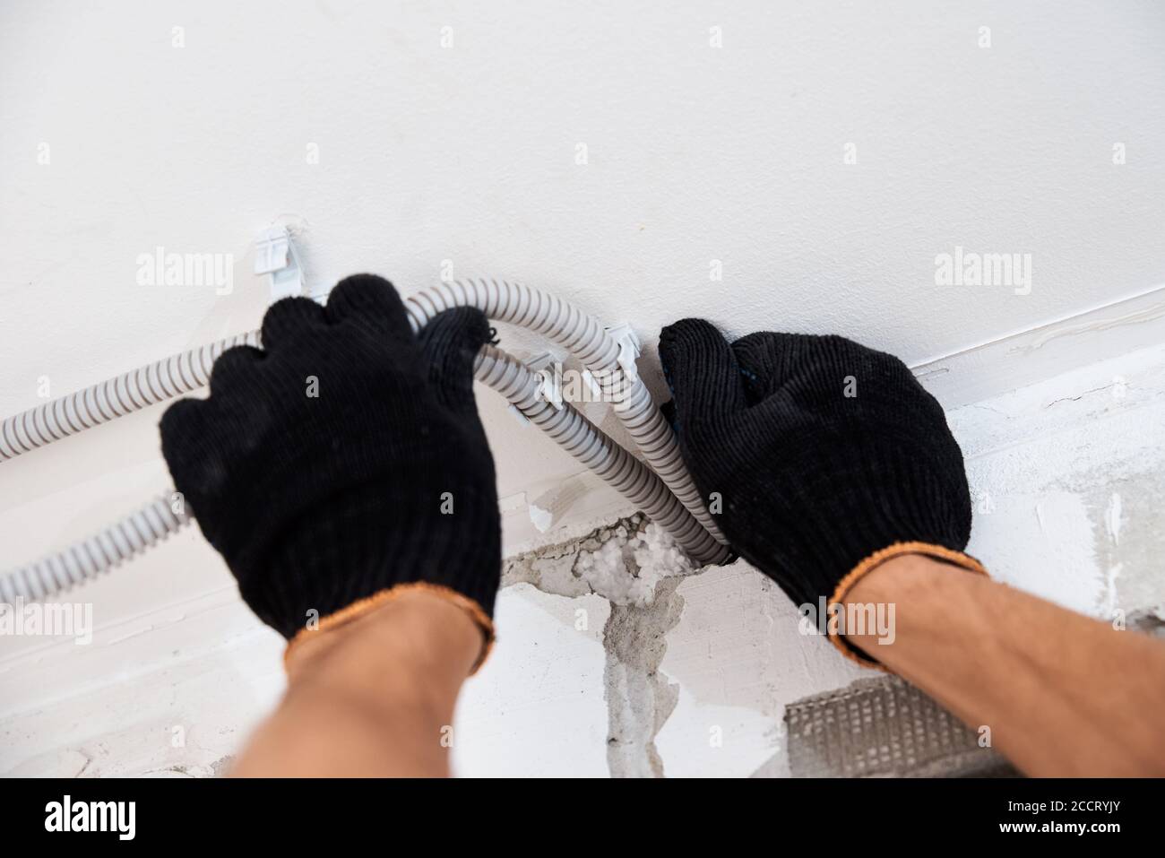 Electrician fixing electric cable to the wall, close up Stock Photo - Alamy