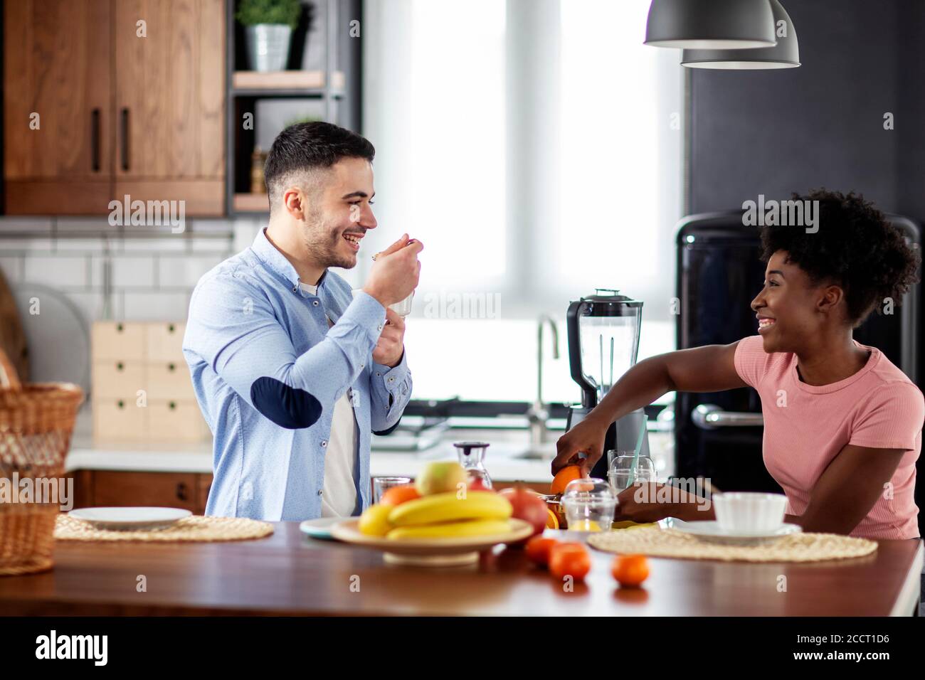 Couple in the kitchen smile and make juice Stock Photo - Alamy
