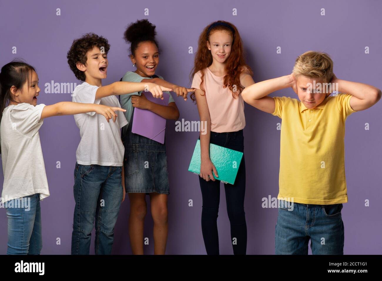 Prevention of bullying. Depressed boy closing ears while his classmates ...