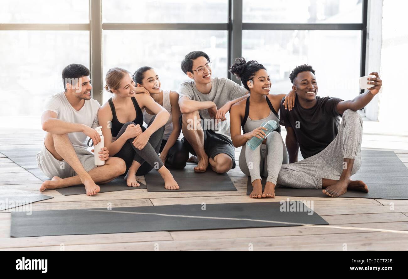 Happy yoga class members taking selfie on smartphone after training in ...