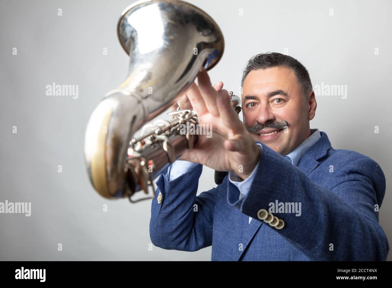 A man, dark, short hair, a long mustache on his shoulder, holds a bass ...