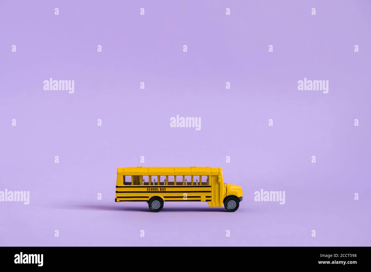 Back to school concept. Traditional yellow school bus on purple ...