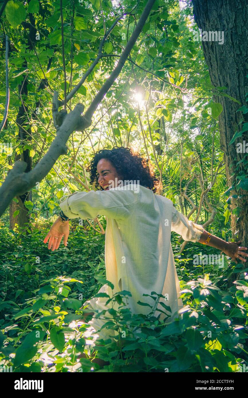 Beautiful young female with curly hair dancing in a park and laughing ...