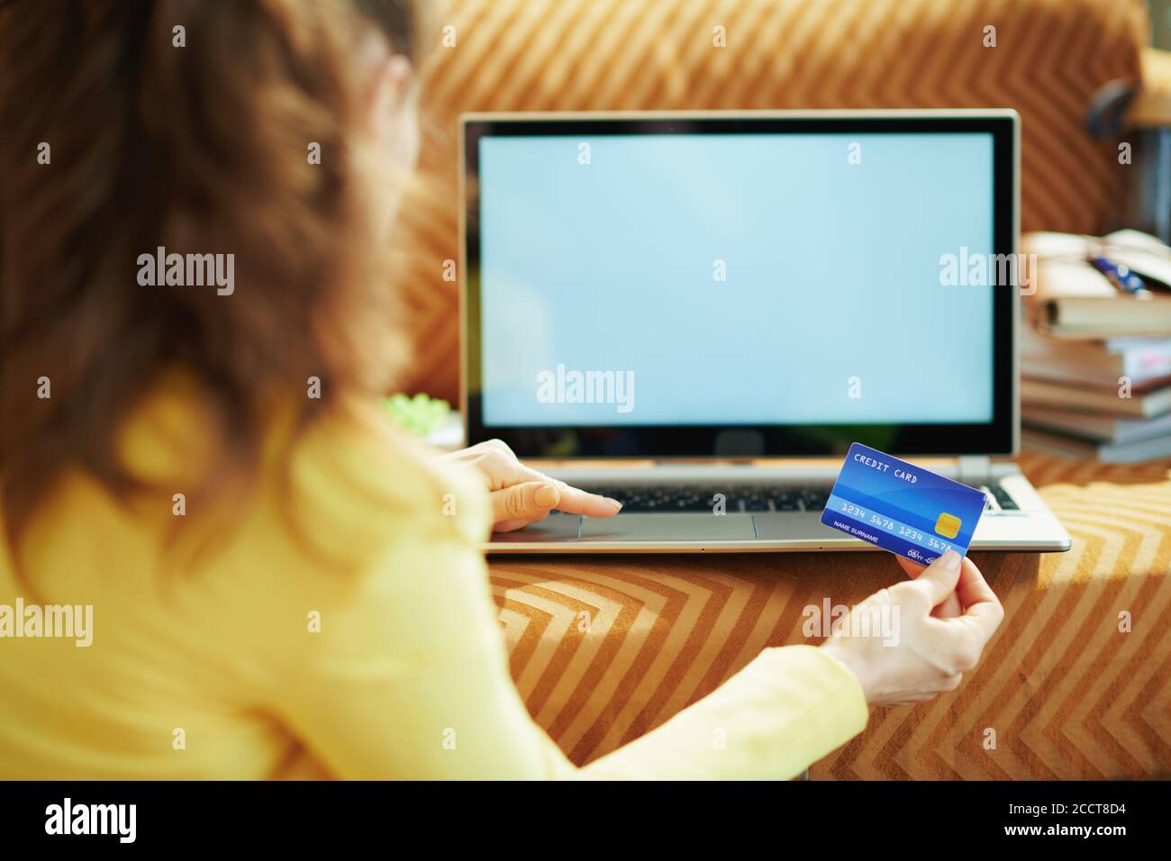 Seen from behind female with credit card and laptop blank screen in the ...