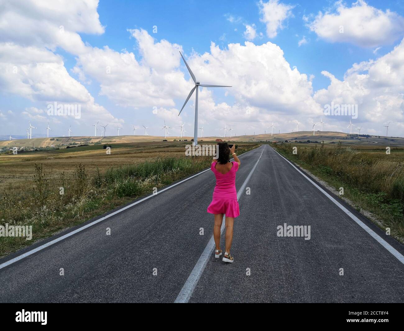 Low angle shot of a young lady taking a photo of a wind turbine Stock ...