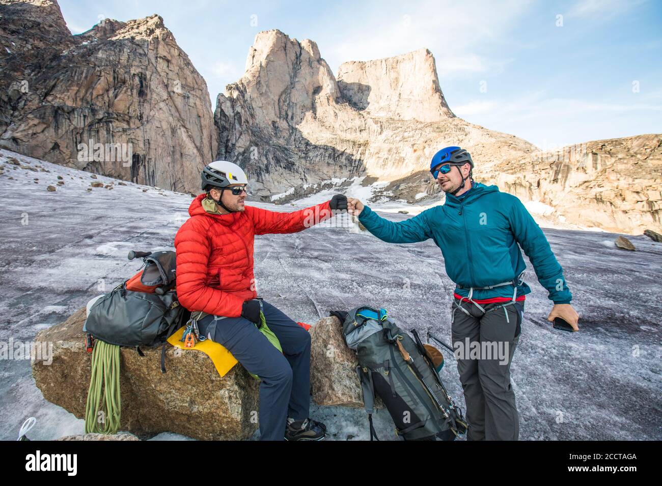 Two climbers fist bump below mountain after a successful climb Stock ...