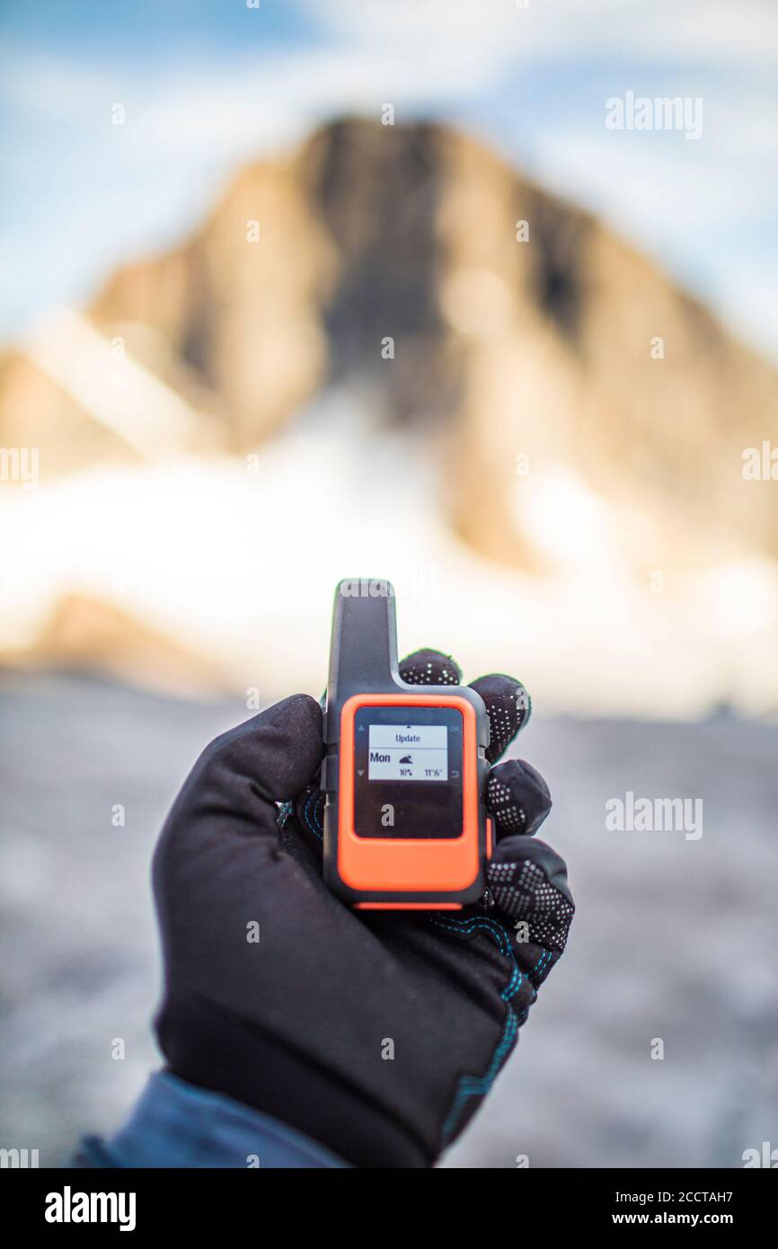 Mountaineer holding mini GPS unit with weather forecast showing Stock ...