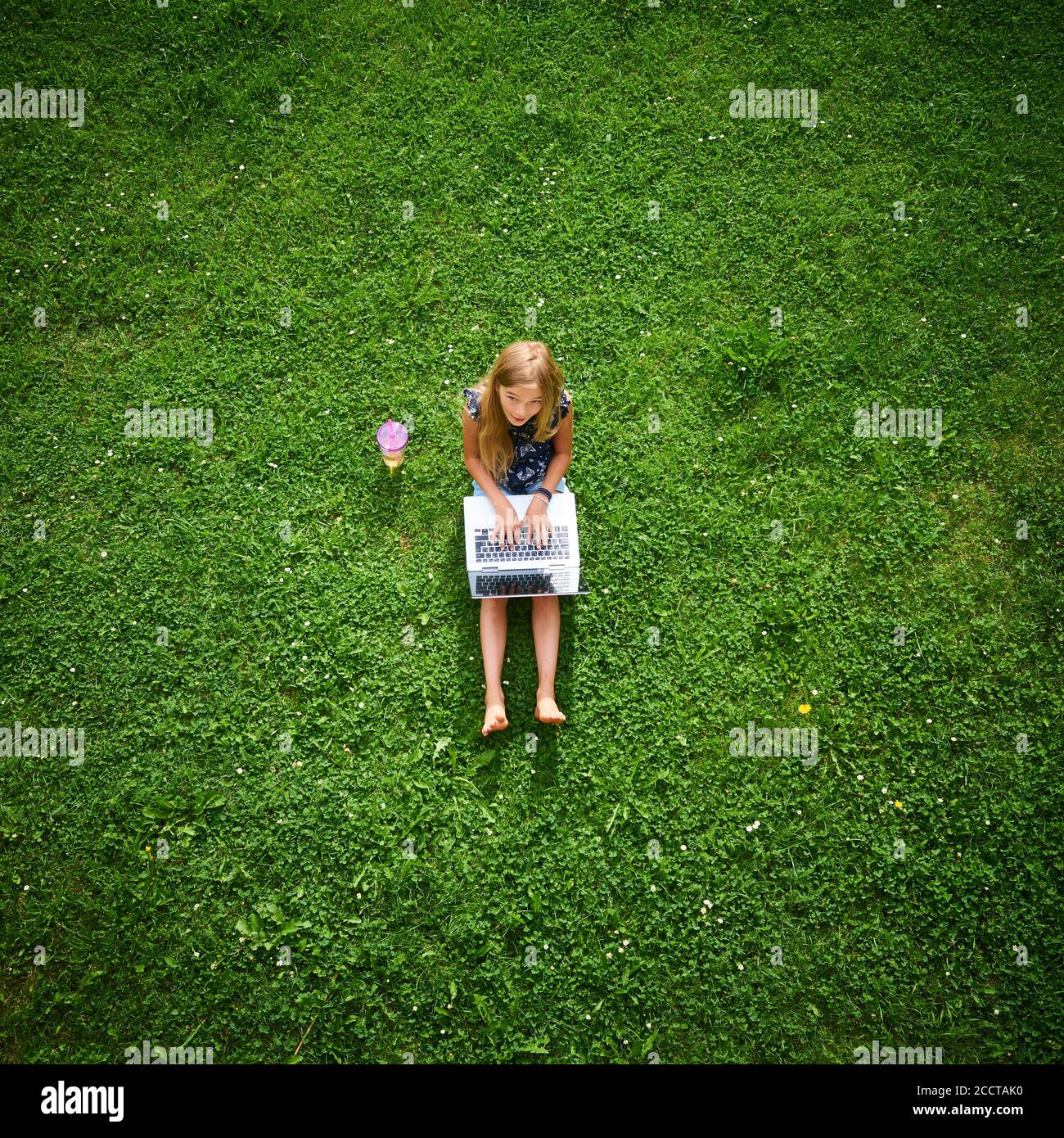 Child blond girl working on laptop. Playing games or watching movie ...