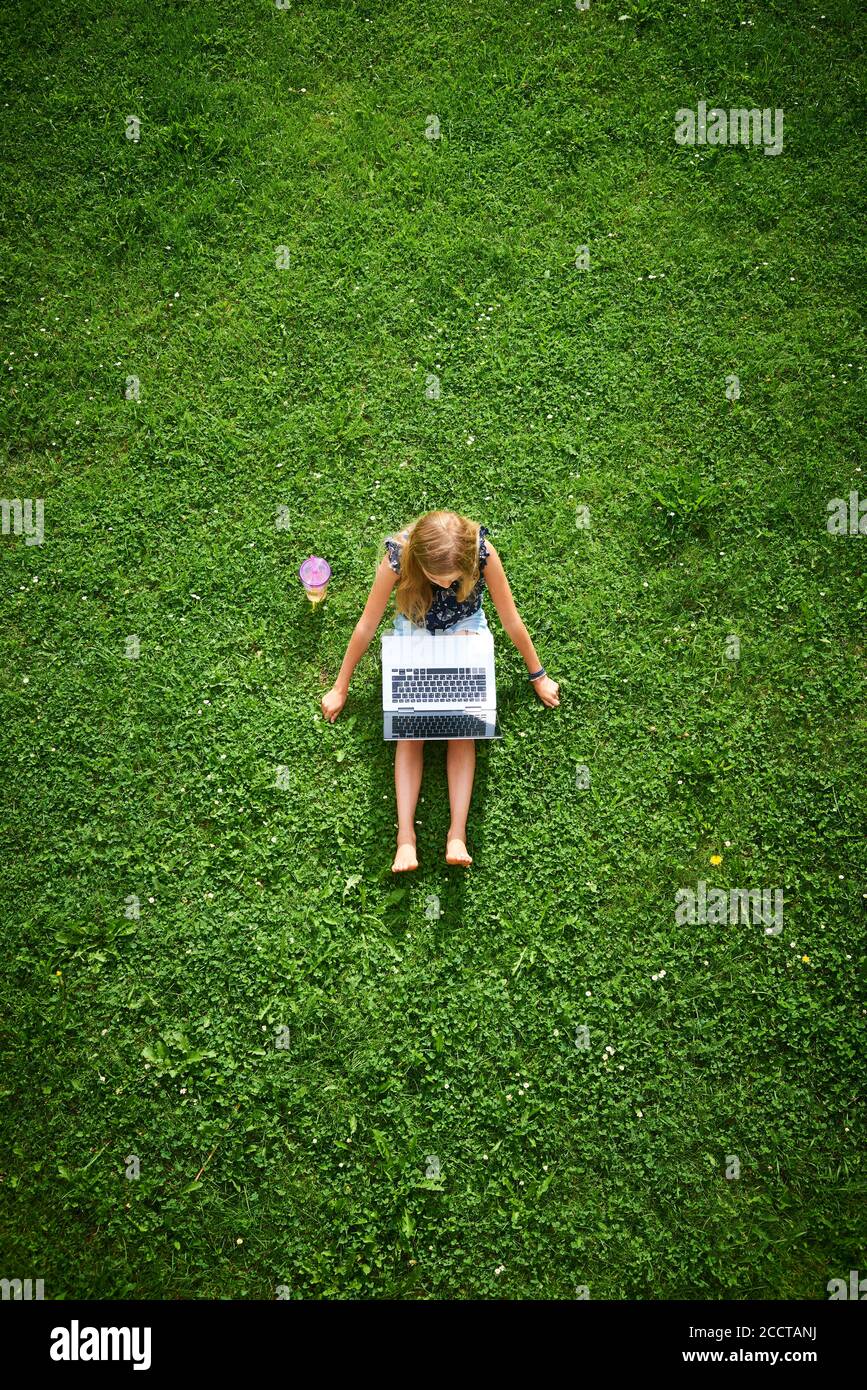 Child blond girl working on laptop. Playing games or watching movie ...