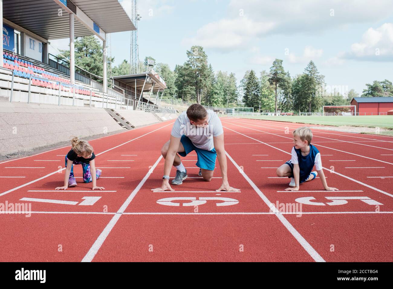 father and his kids getting ready to run on a track to race Stock Photo ...