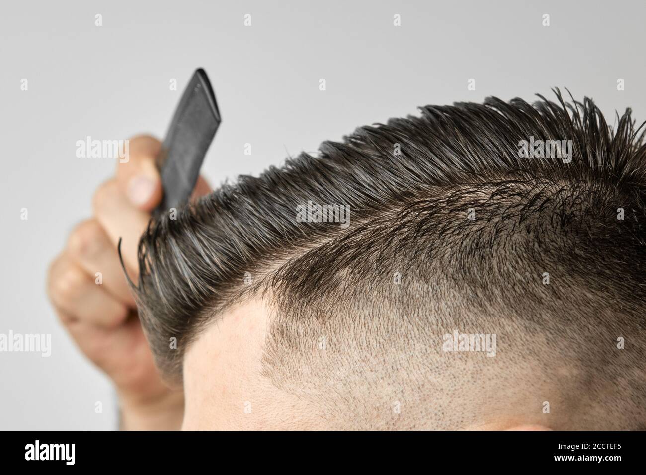 Close up young man combing his hair with a plastic comb. Styling hair ...