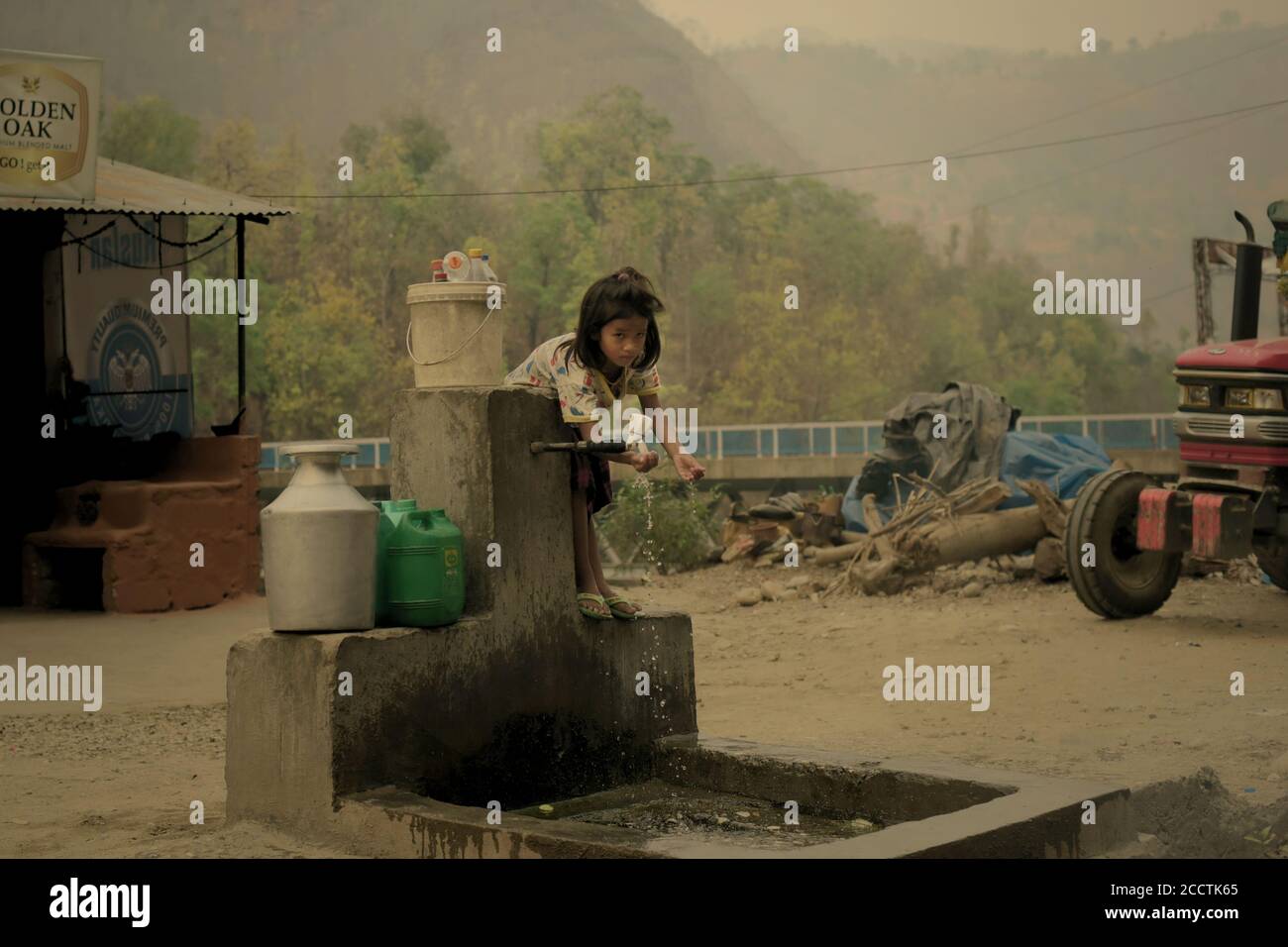A child washing hands at a water station located on the side of the ...