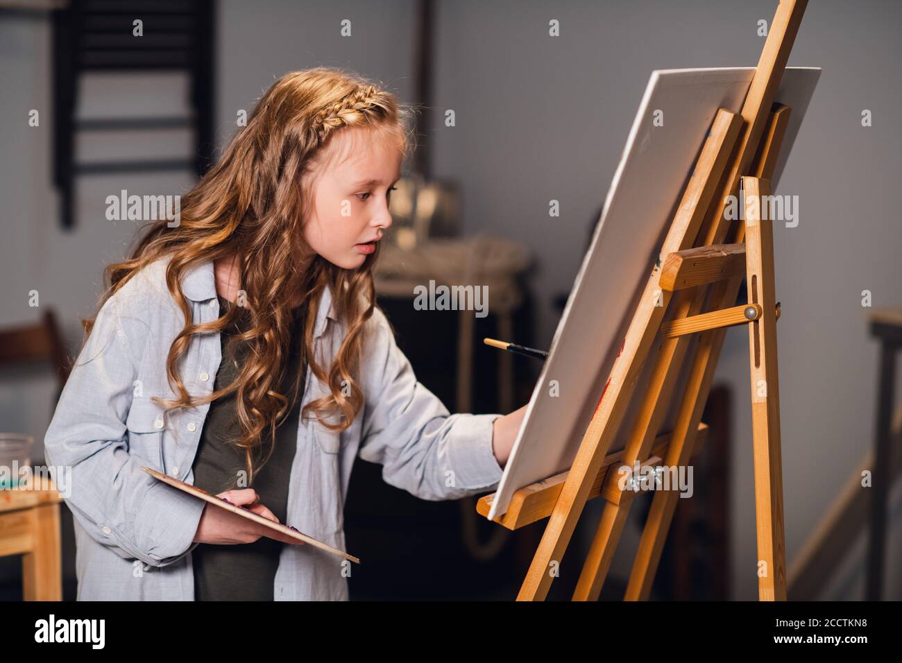 A young cute artist girl is learning to draw in an art workshop. Draws ...