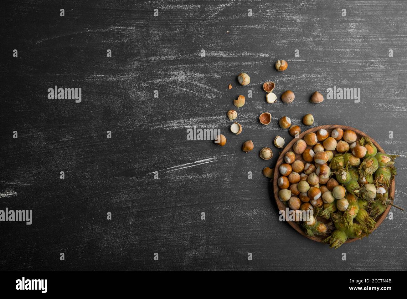 Nuts in green shells in a wooden platter and on the stone table on the ...