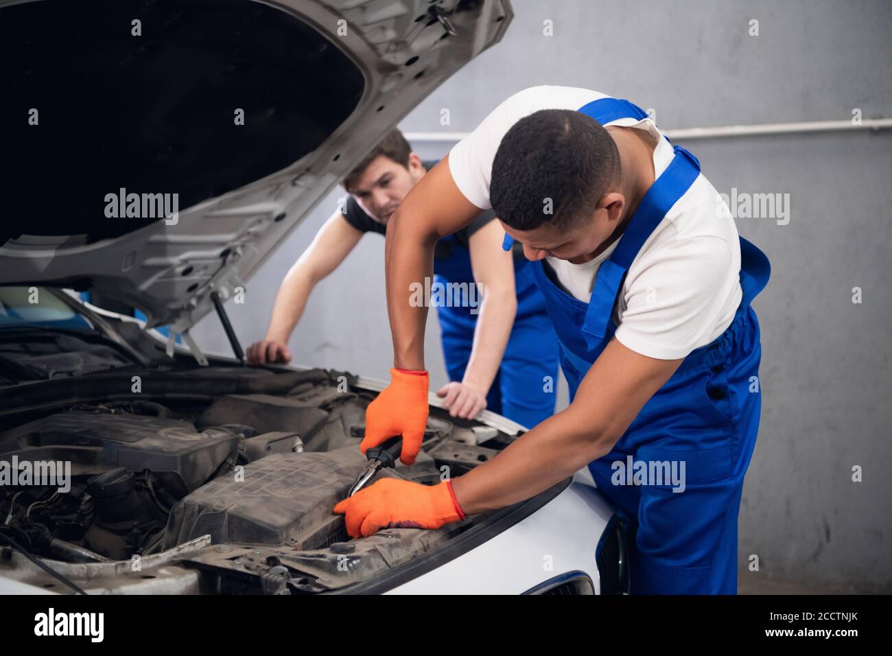 Two mechanics repair a damaged car engine Stock Photo - Alamy