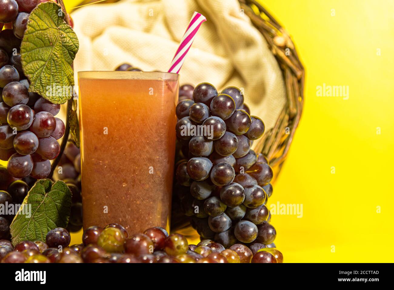 Red grape juice (Vitis vinifera). Yellow background. Bunches of pink ...
