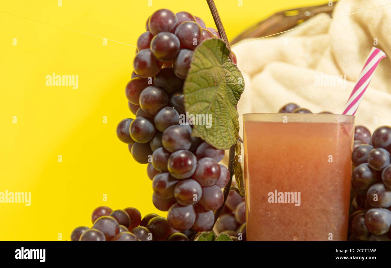 Red grape juice (Vitis vinifera). Yellow background. Bunches of pink ...
