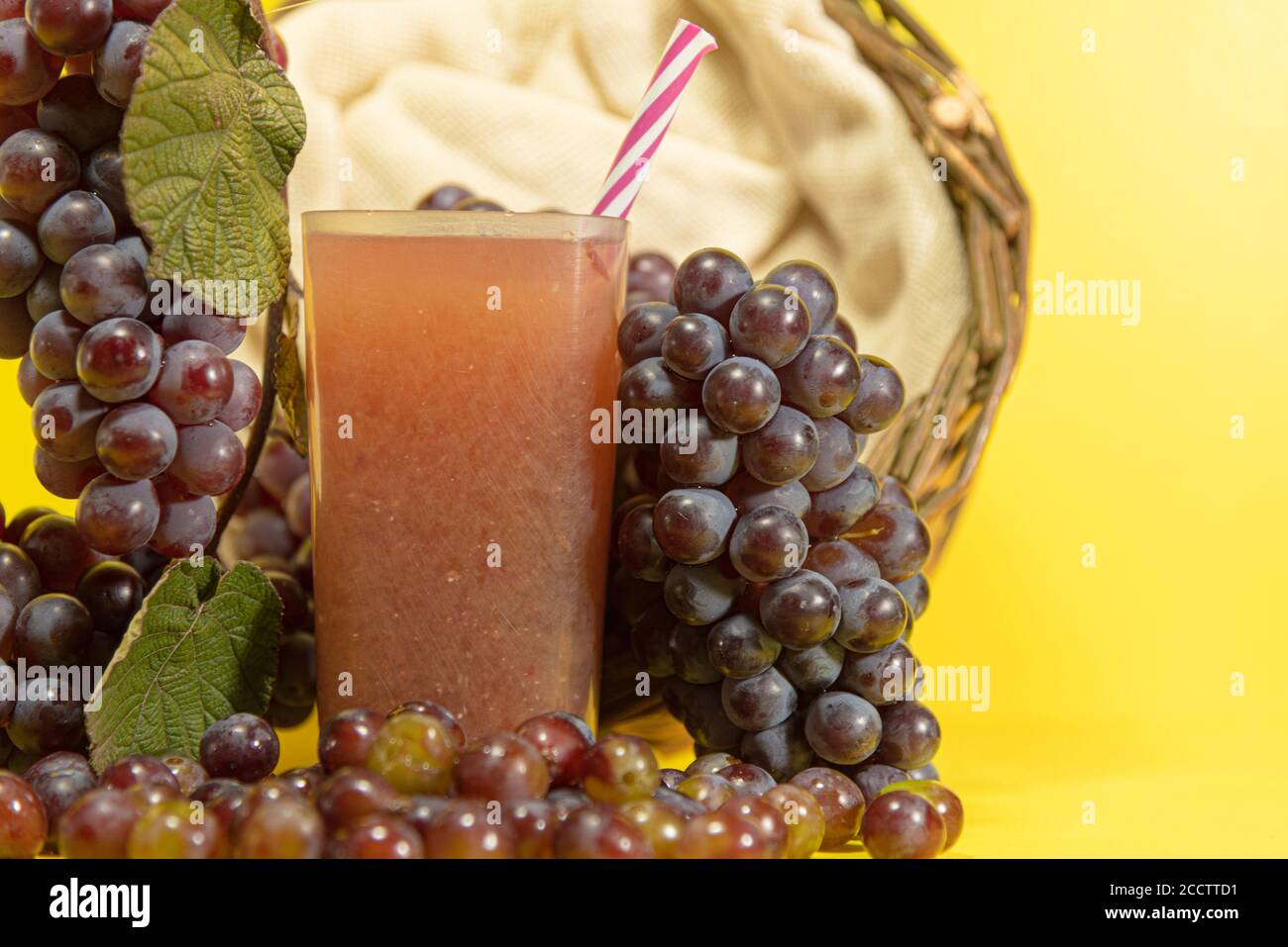 Red grape juice (Vitis vinifera). Yellow background. Bunches of pink ...