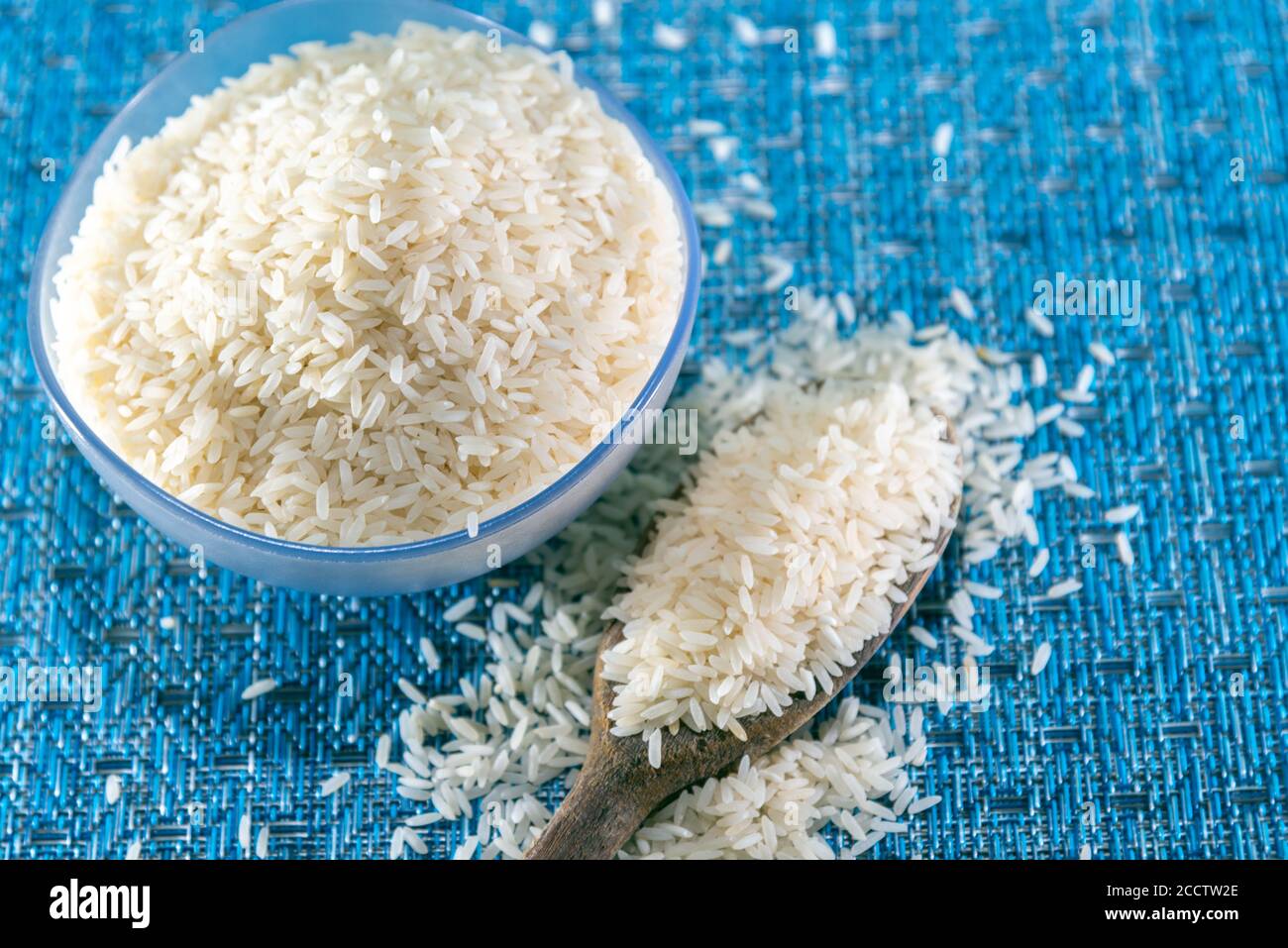 Peeled and processed rice arranged in a small bowl. Wooden scoop with ...