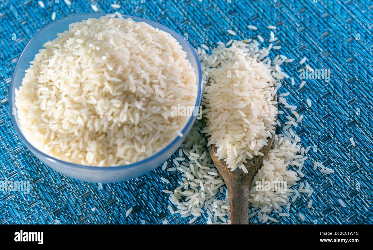 Peeled and processed rice arranged in a small bowl. Wooden scoop with ...