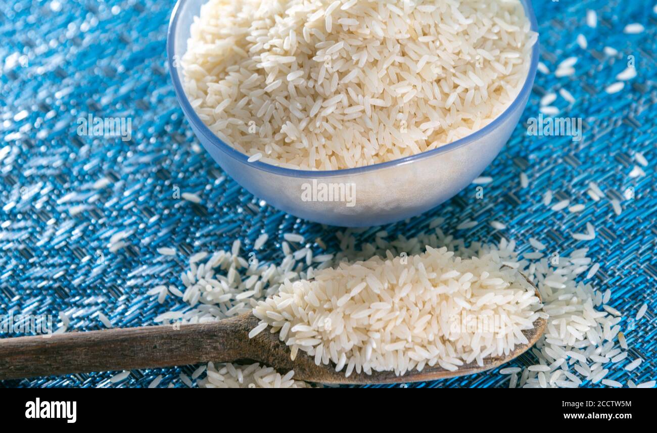 Peeled and processed rice arranged in a small bowl. Wooden scoop with ...