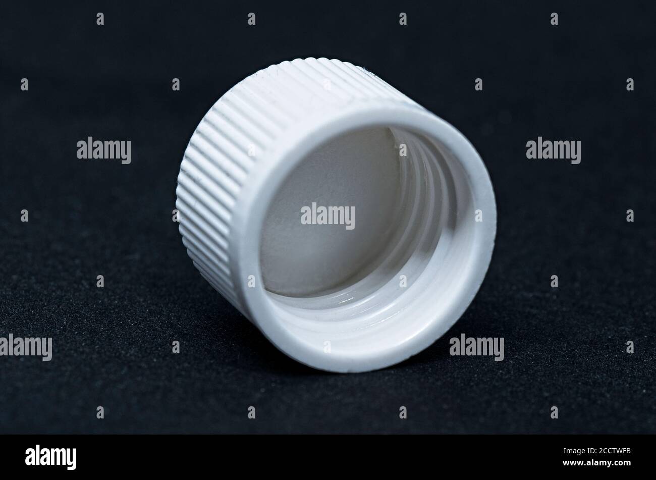 Plastic white cap on black background. Manufactured object Stock Photo ...