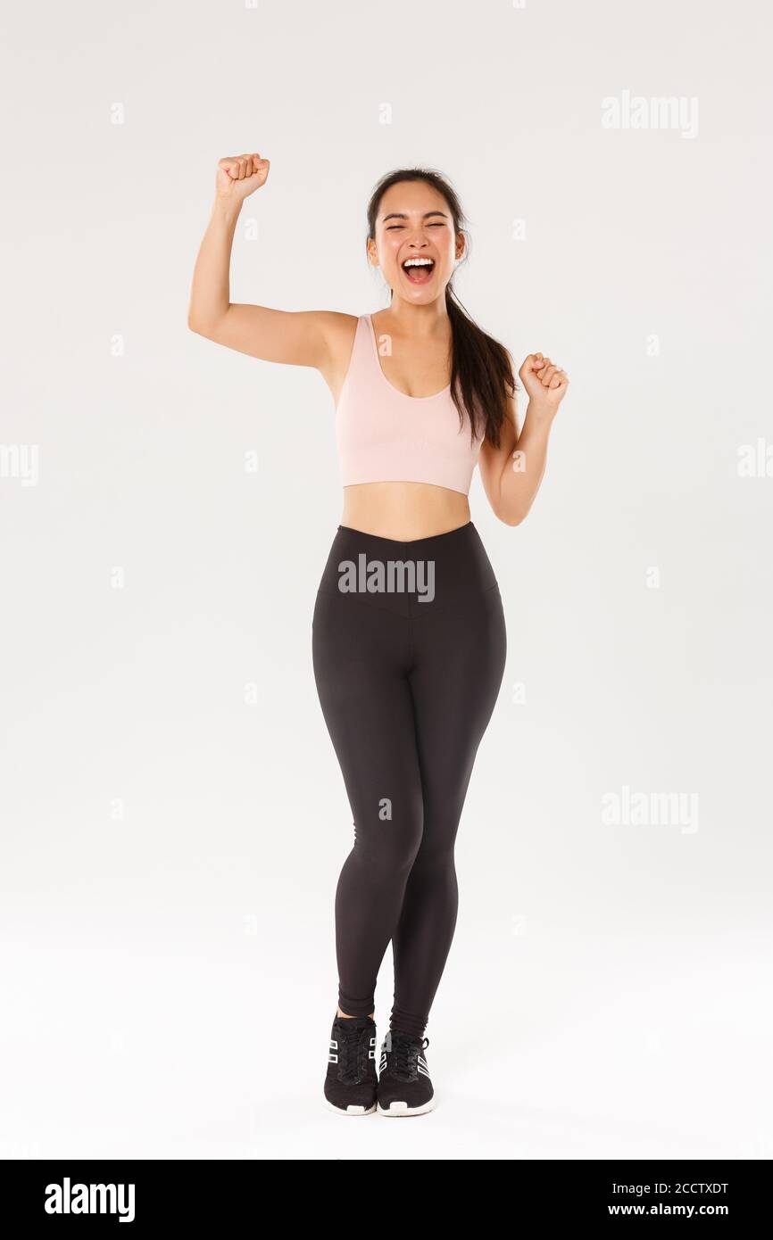 Full length of motivated and excited female athelte, asian fitness girl ...