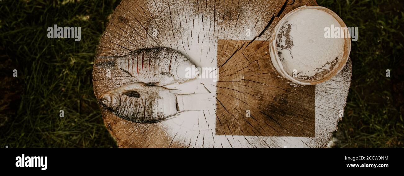 fried fish crucian carp lies on a plate on an old cracked wooden stump ...