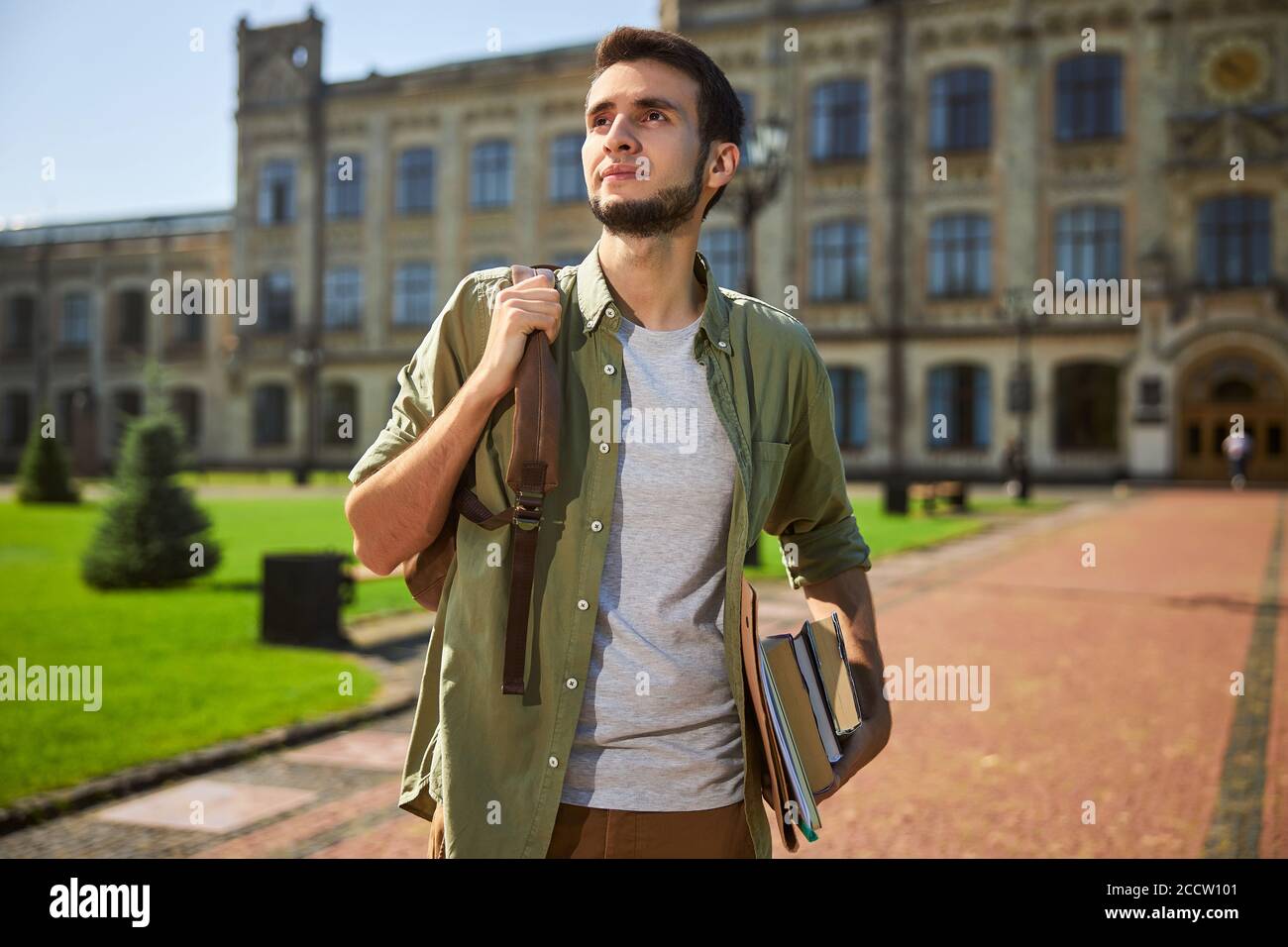 Dreamy attractive male student standing alone outdoors Stock Photo - Alamy
