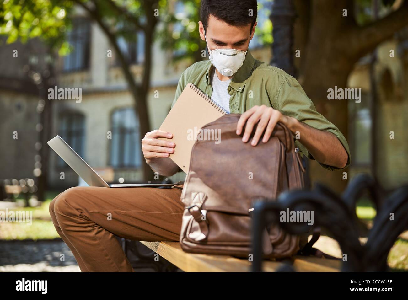 Serious student putting a notebook into a backpack Stock Photo - Alamy