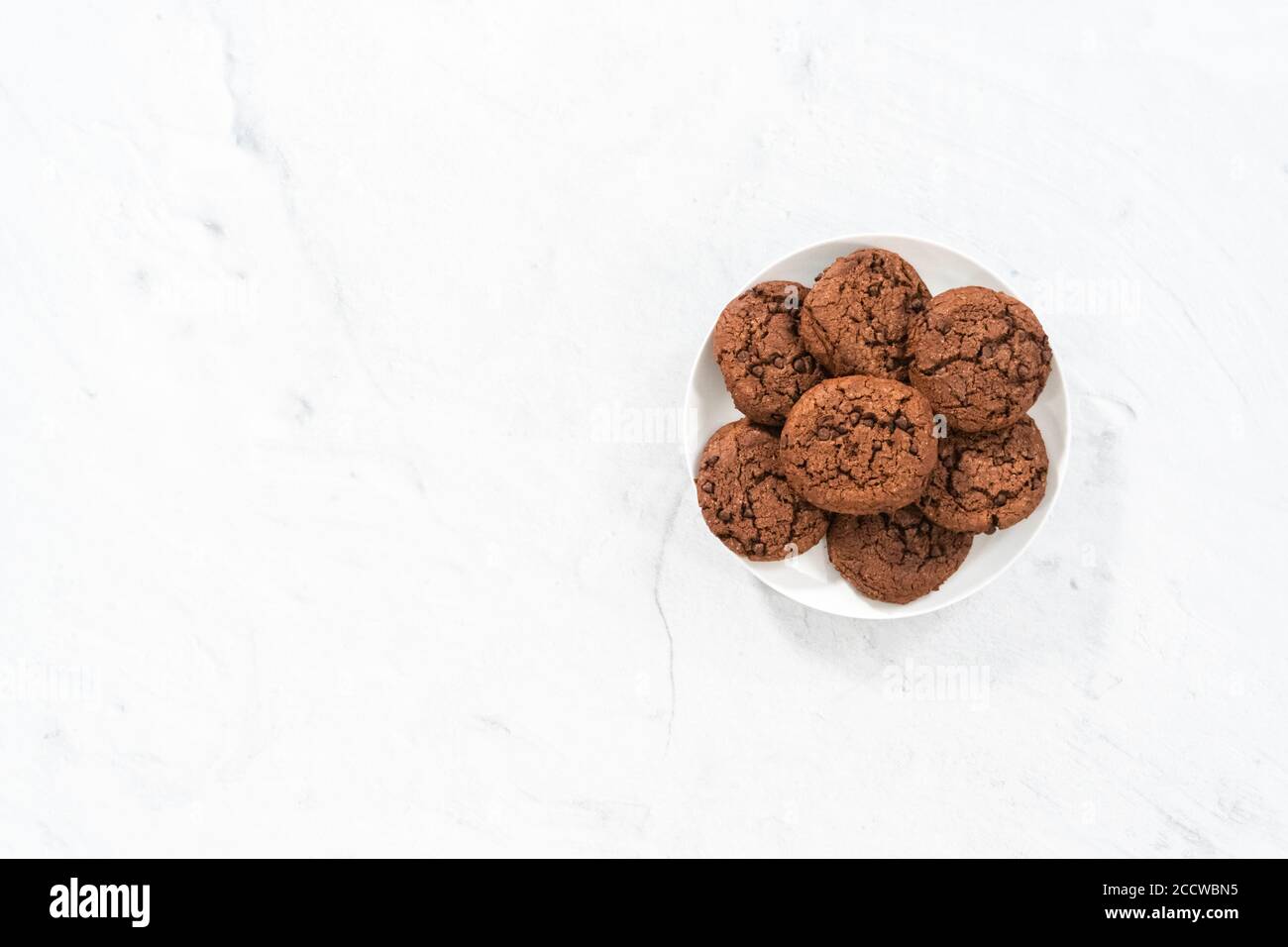 Flat lay. Freshly baked double chocolate chip cookies on a white plate ...