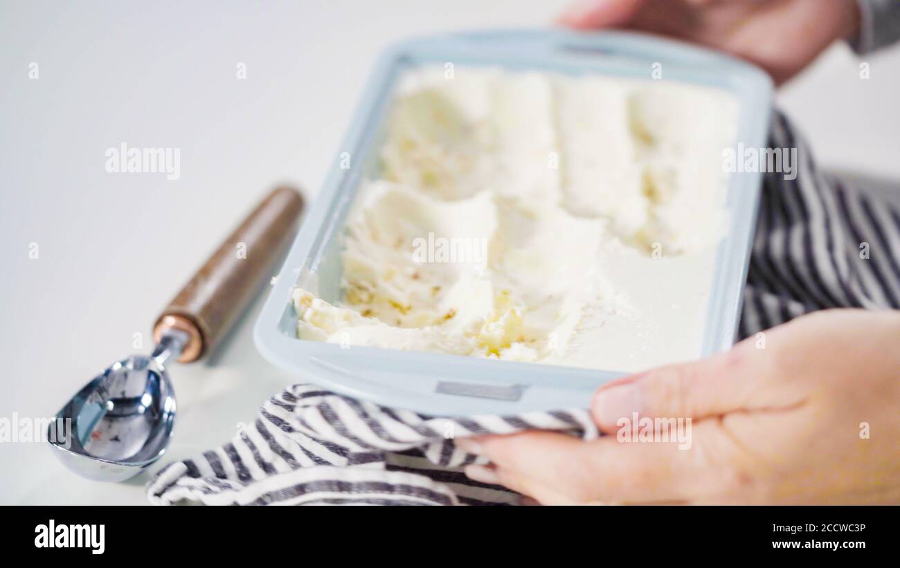 Scooping homemade coconut ice cream into a glass ice cream bowl Stock ...