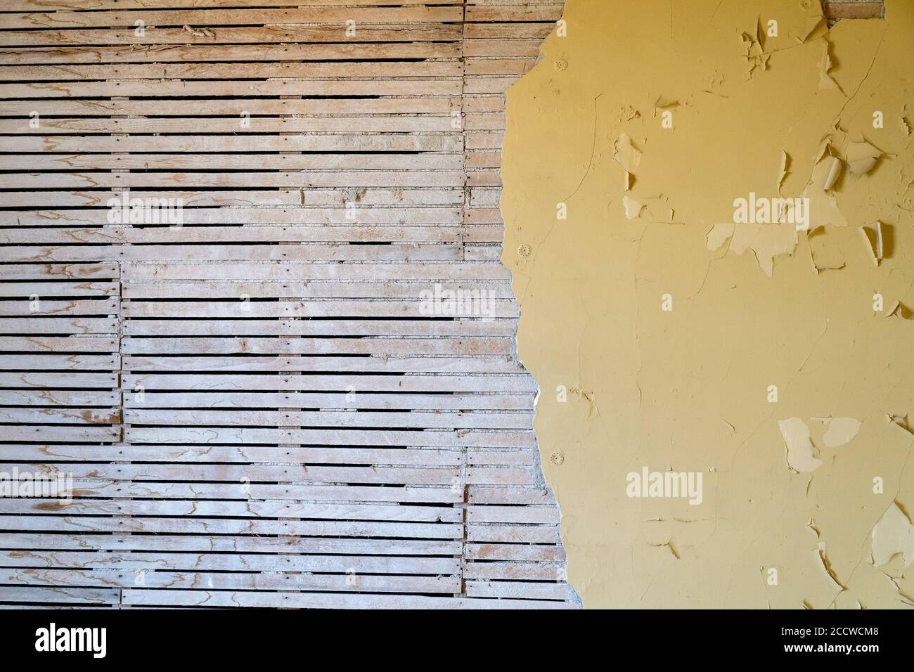 Exposed beams, framing and studs with peeling yellow paint on the wall ...