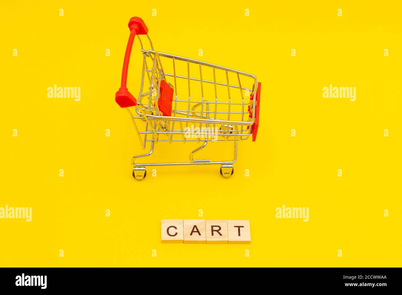 Word CART made from wooden cubes on yellow background with toys ...