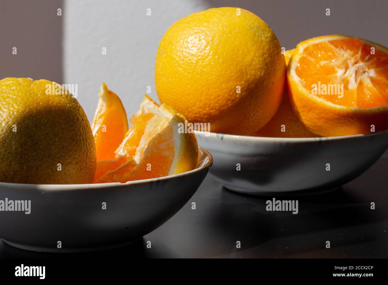 Oranges for breakfast. Healthy fruit in different plates on a black ...