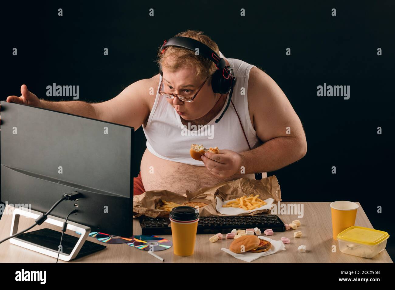funny plump man staring at the screen of the computer and eating a ...