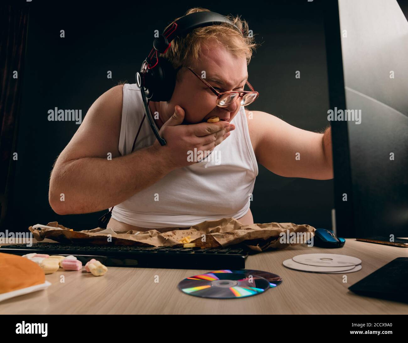 man in headphones looking at the screen and eating food with appetite ...