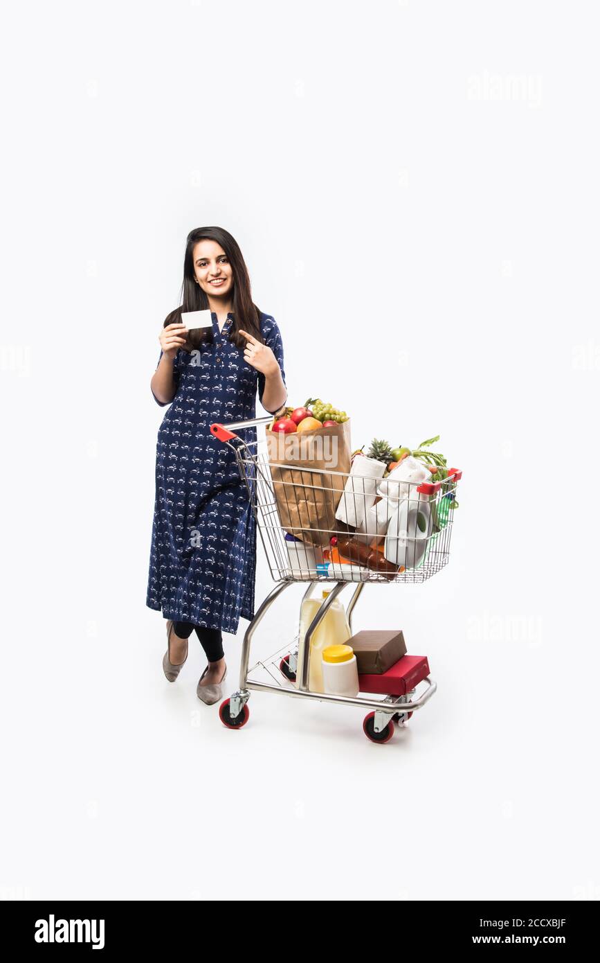 Indian young woman with shopping cart or trolly full of grocery ...