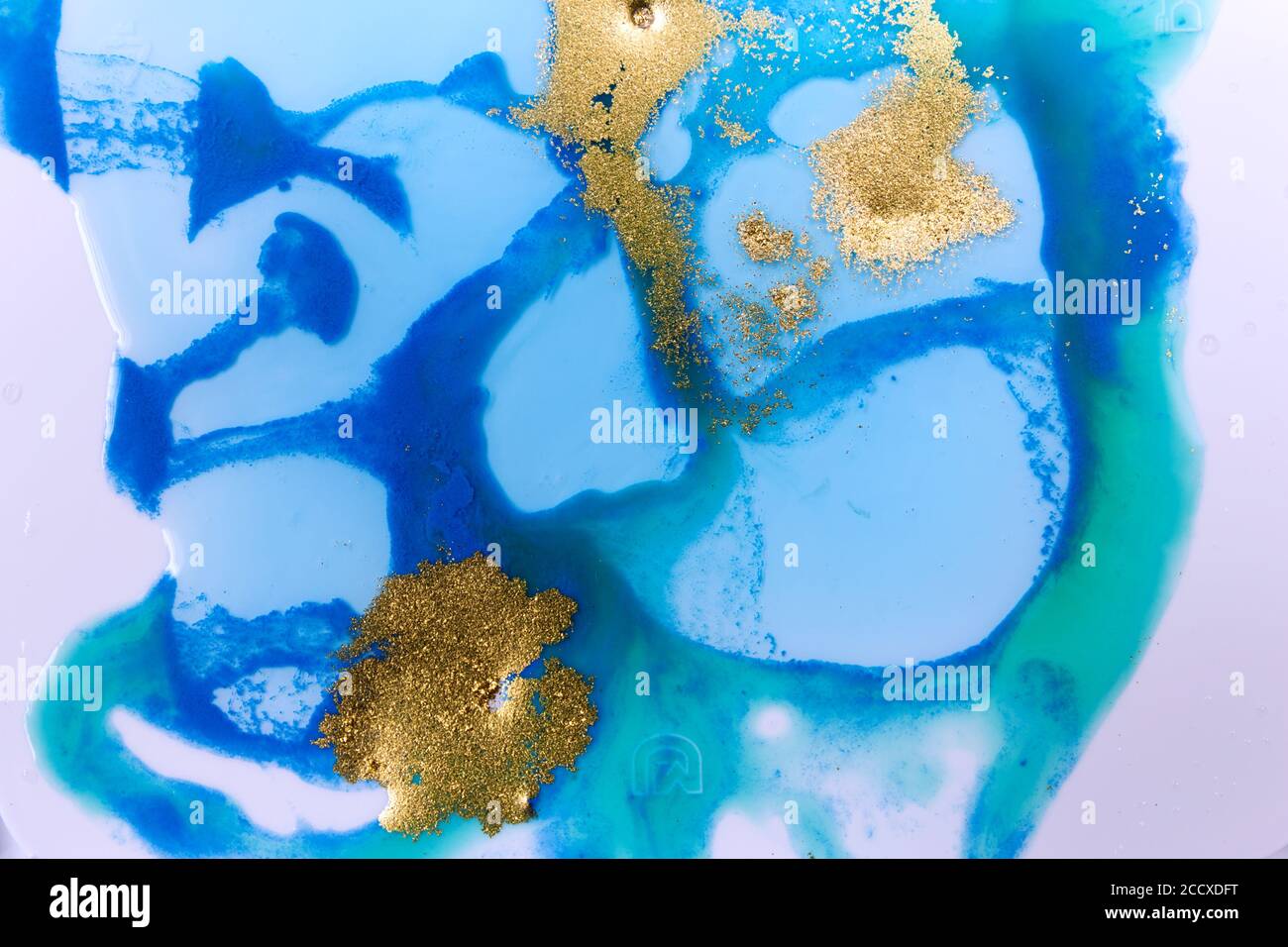Gold and blue mixed inks splattered on white paper background Stock ...