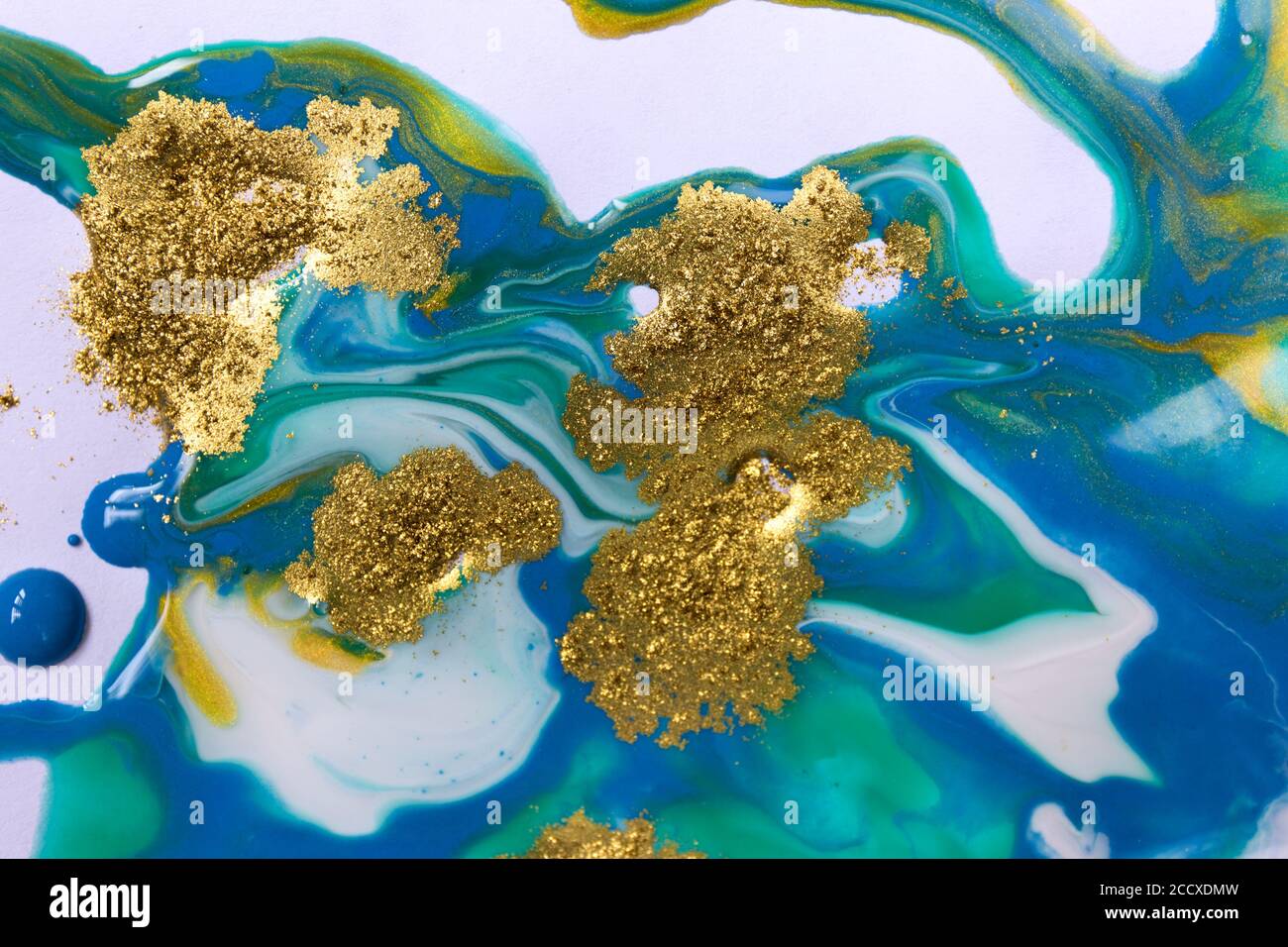 Gold and blue mixed inks splattered on white paper background Stock ...