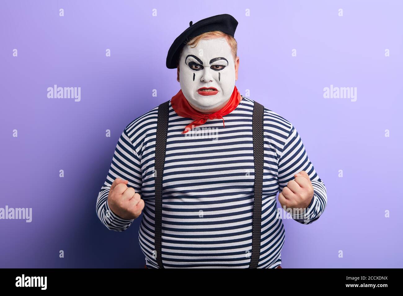 Mime man with clenched fists looking angry at camera, isolated blue ...